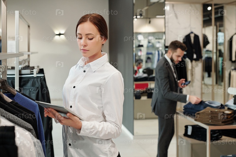 Фотография на тему Pretty young shop assistant of boutique scrolling ...